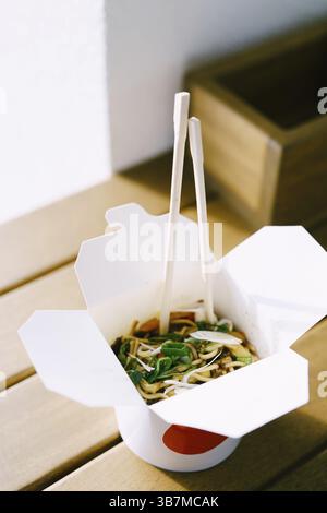 Noodles with pork and vegetables in take-out box on wooden table Stock ...