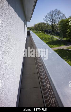 Narrow brick balcony with metal railings, wooden chair and door with ...