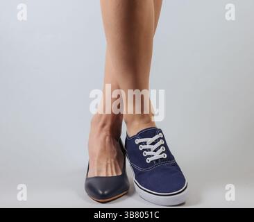 Slim woman's legs in two different shoes with heels and sneakers on ...