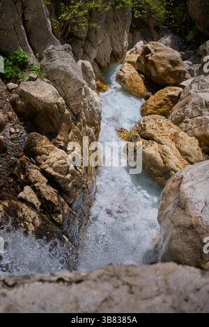 Powerful mountain stream cascading through narrow rocky limestone gorge ...