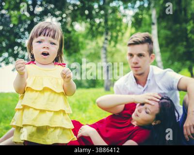 naughty little baby and parents with tired and discontented expression ...