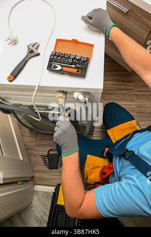 Repairman repairing washing machine in the kitchen Stock Photo - Alamy