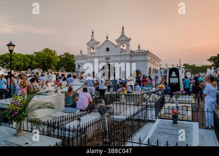 Colombians stand among tombs as they attend an evening mass during the ...