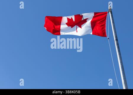 Waving flag of Canada against blue sky Stock Photo - Alamy