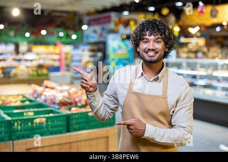 Smiling grocery store worker inviting customers in supermarker Stock ...