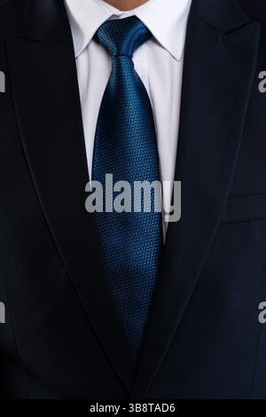 Close-up of a tailored blue suit jacket with a black fabric patch ...