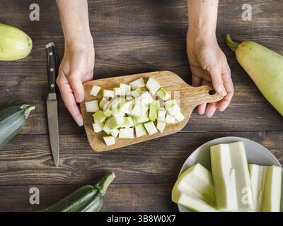 Zucchini harvest. Woman slices zucchini cubes for freezing on wooden ...