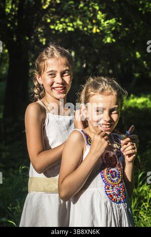 Two beautiful daughters hugging and dancing in the park Stock Photo - Alamy