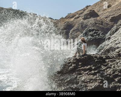 Woman splashes water while sitting on blue float in pool surrounded by ...