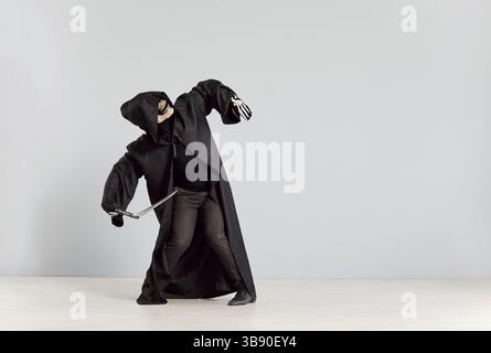 Man in grim reaper death costume isolated on studio gray background ...