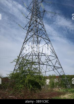 A towering electricity pylon holding up the high-voltage overhead power ...