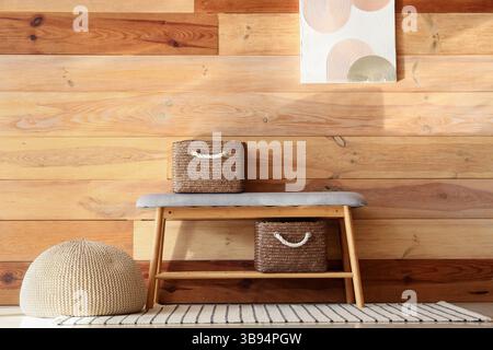 Baskets on bench and pouf near wooden wall in room Stock Photo - Alamy