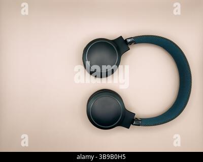 White wireless earbuds lie on a dark textured surface. One earbud shows ...