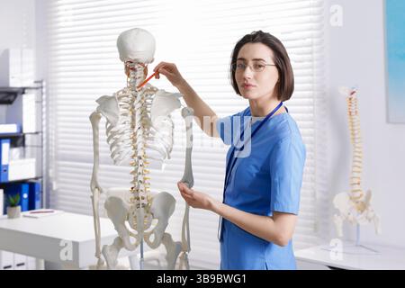 Doctor pointing at parts of human skeleton model in clinic Stock Photo ...