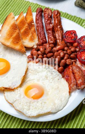 Breakfast with fried eggs, sausages and green peas on white plate Stock ...