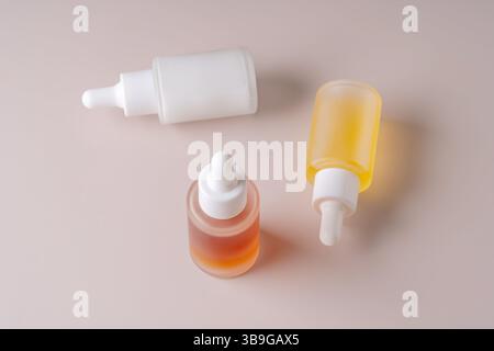 Three glass bottles containing liquids, one glass dropper, green leaves ...