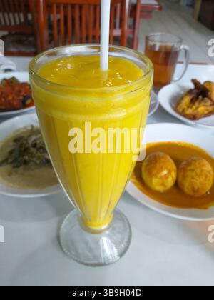 Mango Juice with Indonesian Nasi Padang dishes on a restaurant table ...