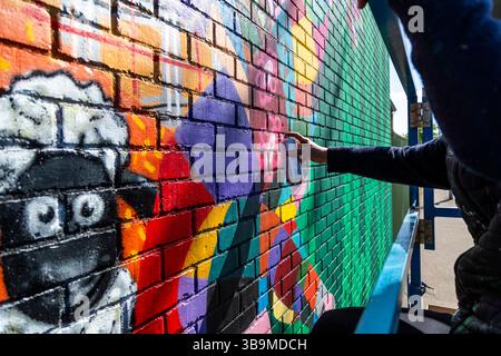 Artist Louis Masai working on a mural for Hit the North Translink ...