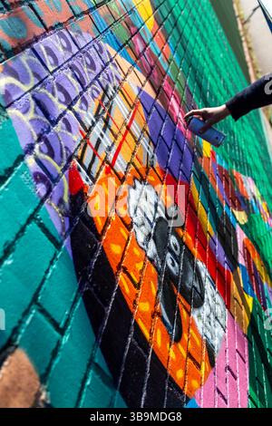 Artist Louis Masai working on a mural for Hit the North Translink ...
