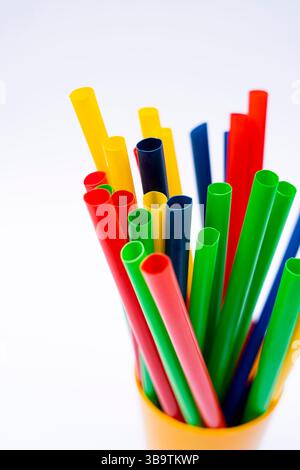 Multicolored party drinking straws arranged into a circle on yellow ...