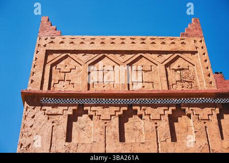 A traditional clay kasbah is set against a clear blue sky with ...