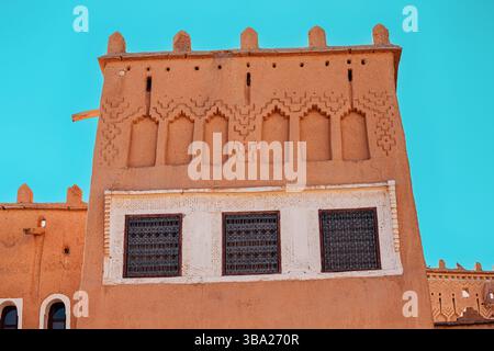 A traditional clay kasbah is set against a clear blue sky with ...