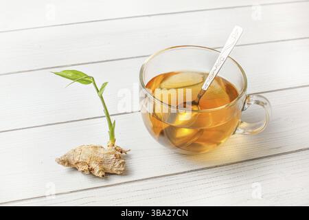 Glass cup of freshly brewed amber tea, dry ginger root with green ...