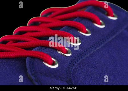 A fragment of a blue sneaker with red laces close up. Sneaker texture ...