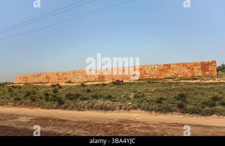 Orange red bricks made from local clay arranged in wide stack, ready ...