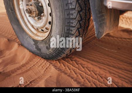 4wd vehicle tyre, dirty from dust - track print visible in red sand ...