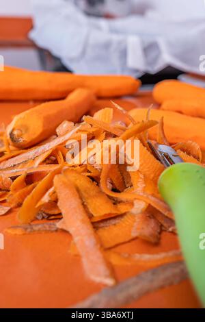 Peeling ripe orange carrot with vegetable peeler. Flat lay view. Fresh ...