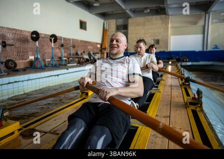 Focused forced rowing athletes train intensely on rowing simulator ...