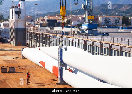 Loading wind generator blades using a crane onto a cargo ship at a ...
