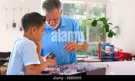 A grandad and grandson making a robot together at home. Education in ...