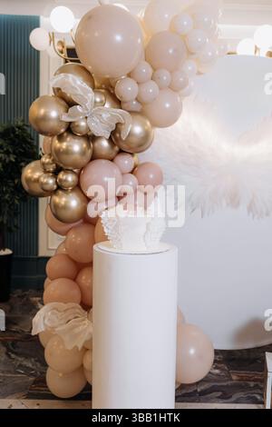 White cake for celebrating a child's baptism. Sweet cake with white wings. Photo zone for a ...