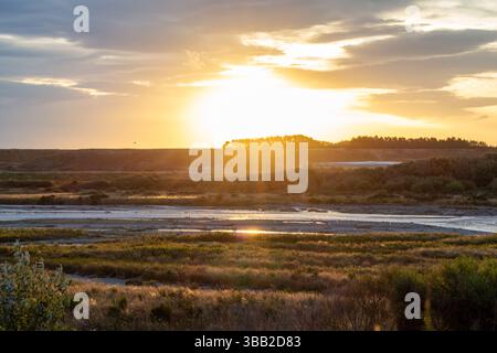 Sunset over a serene beach with a winding stream and distant islands ...