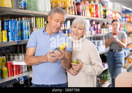 Man and woman purchasers choosing cool drink in supermarket Stock Photo ...