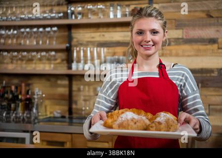 Woman in an apron presenting freshly baked artisan sourdough bread ...