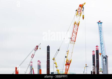 Protruding arrows of port cranes against a cloudy sky Stock Photo - Alamy