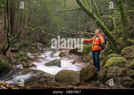 Man embraces the wild beauty of Glenmalure Valley beside a rushing ...