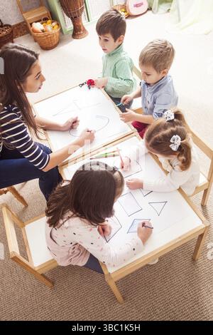 Overhead view of children in kindergarten learn letters and shapes ...