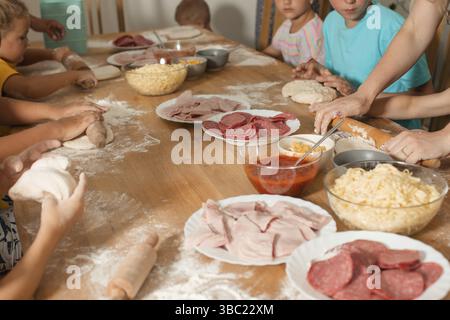 Two female tutors show children how to make pizza Stock Photo - Alamy
