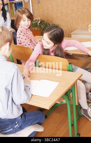 Cute school girl helping her classmate during lesson Stock Photo - Alamy