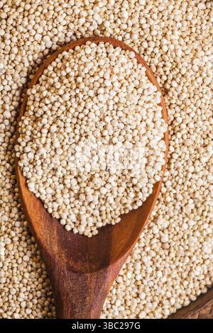 quinoa seeds in bowl and spoon on colored background. Healthy kinwa in ...