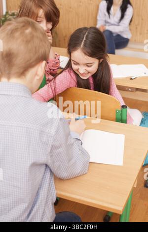 Cute school girl helping her classmate during lesson Stock Photo - Alamy