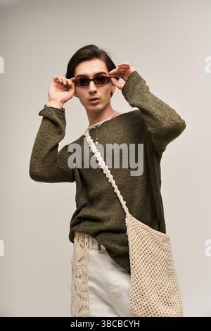 A young non binary individual poses stylishly on a stool, expressing ...