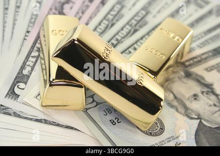 Three large gold bars on a bundle of dollar notes Stock Photo - Alamy
