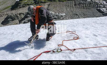 one male mountain guide installing a pulley system for crevasse rescue ...
