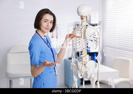 Doctor pointing at parts of human skeleton model in clinic Stock Photo ...