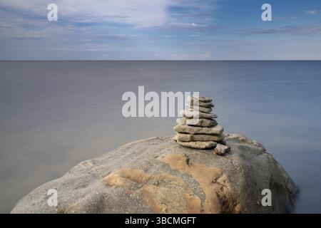 A meditative rock cairn on top of a boulder with long exposure ocean ...